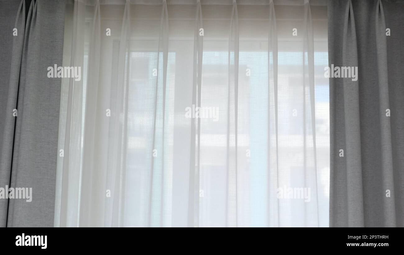 Voile curtain in front of window with grey curtains to either side ...