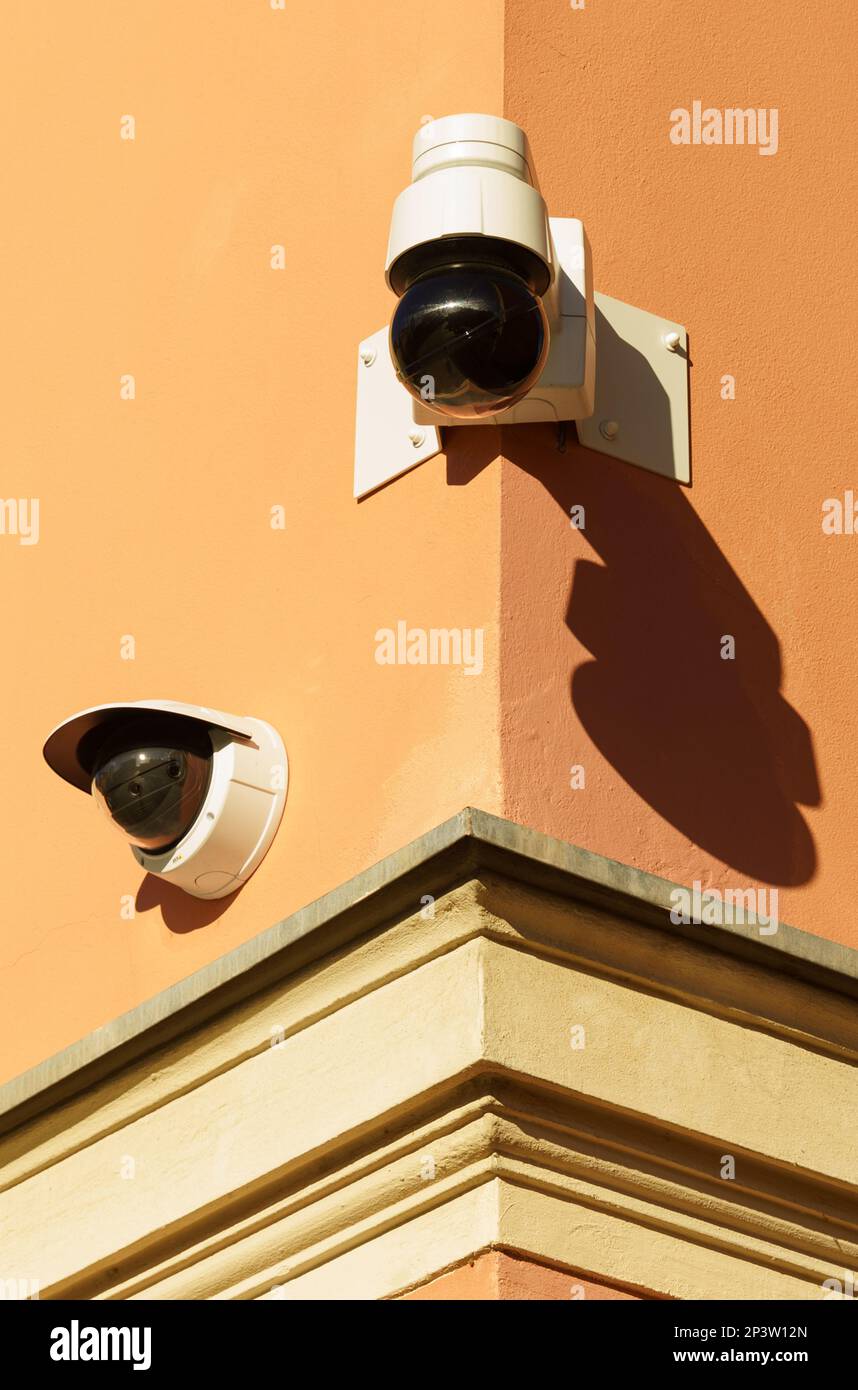 Surveillance cameras are installed on the orange wall of the building ...