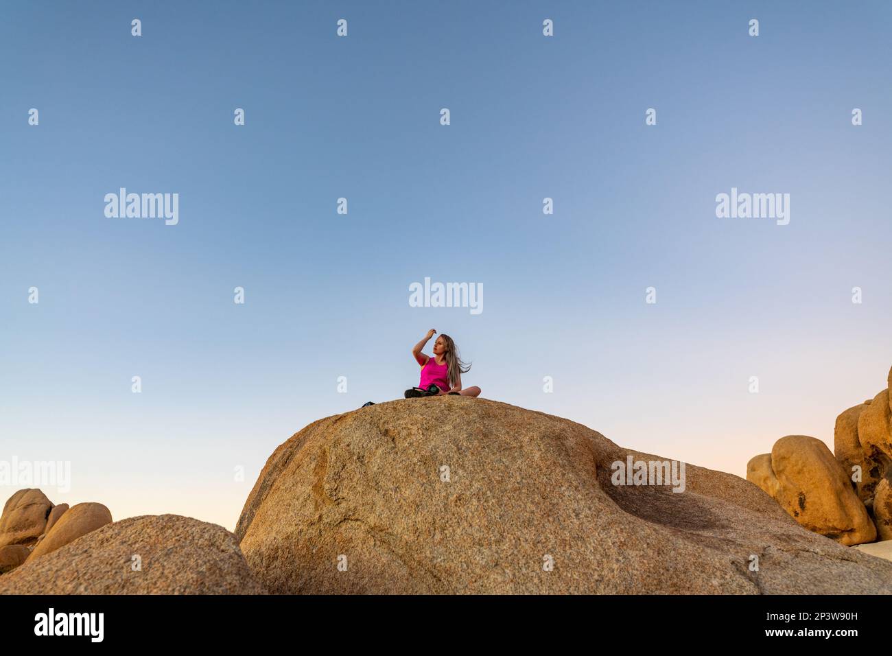 Tourist hiker seen at sunset in Joshua Tree National Park with bright ...