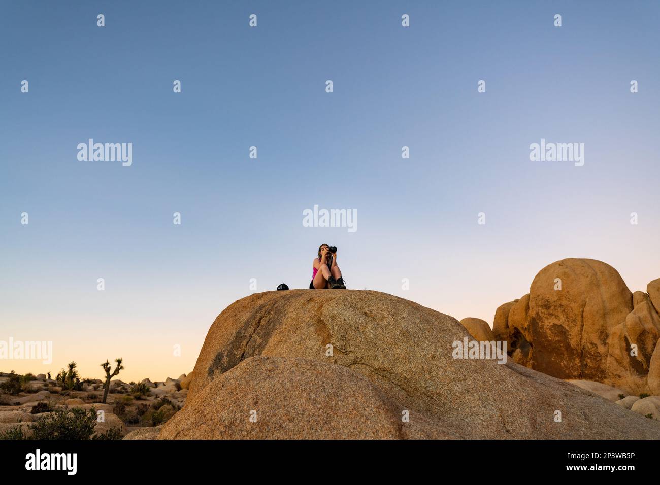 Tourist hiker seen at sunset in Joshua Tree National Park with bright ...