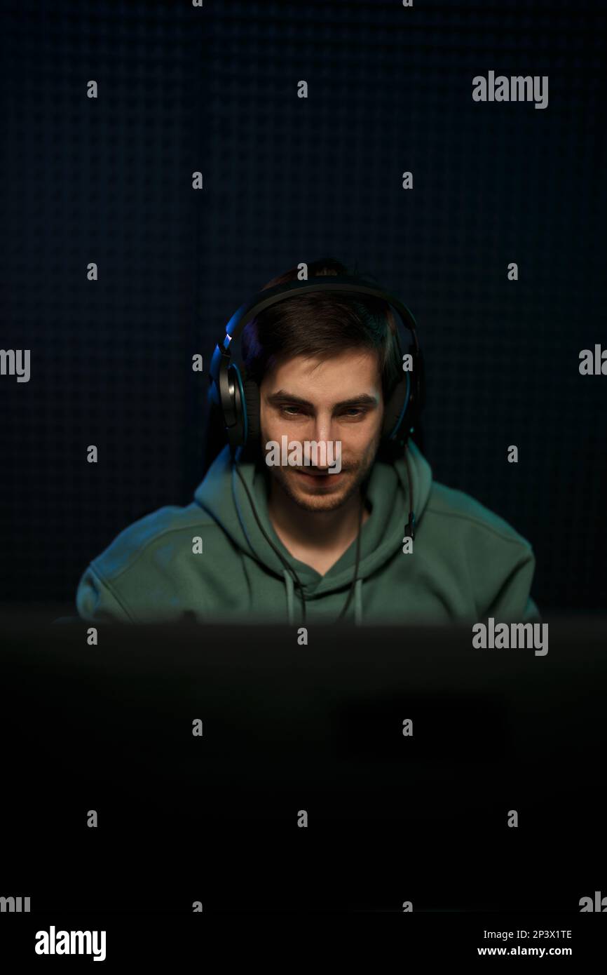 Cheerful male cybersport gamer sitting with hands behind head after ...