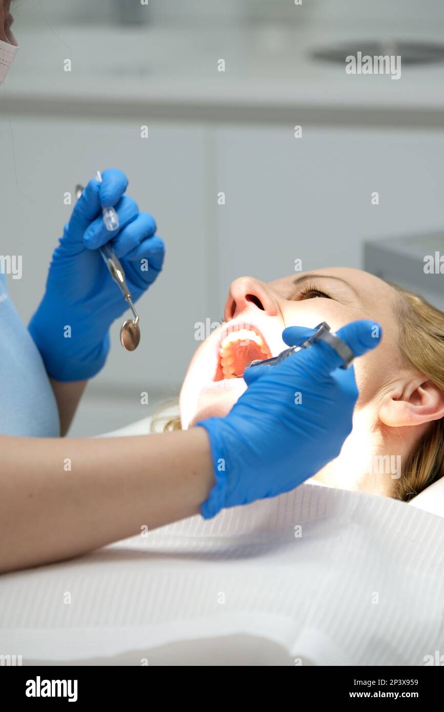 Dentist making injection in gum of female patient in clinic. a doctor ...