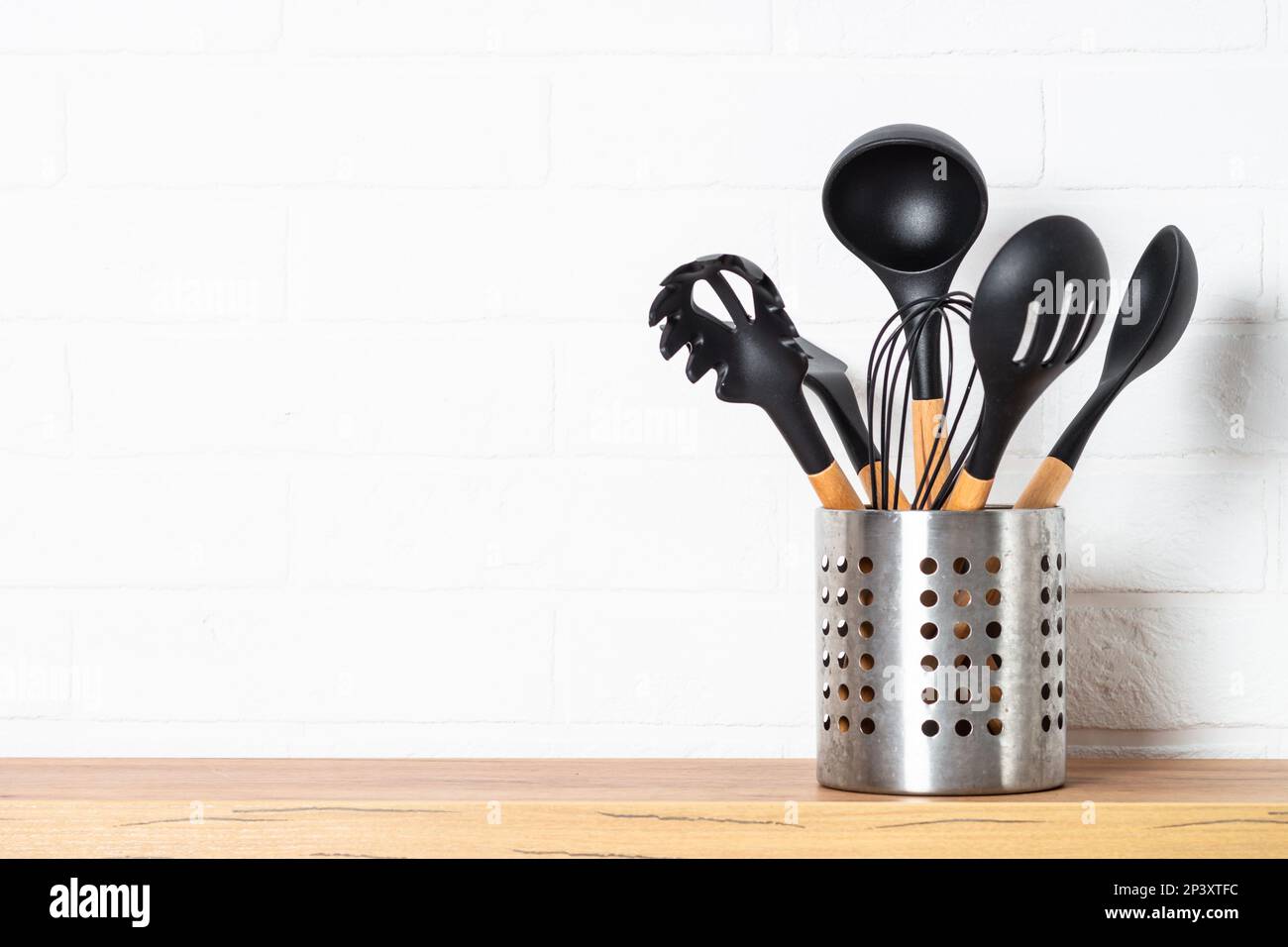 Kitchen utensils in container near white wall Stock Photo - Alamy