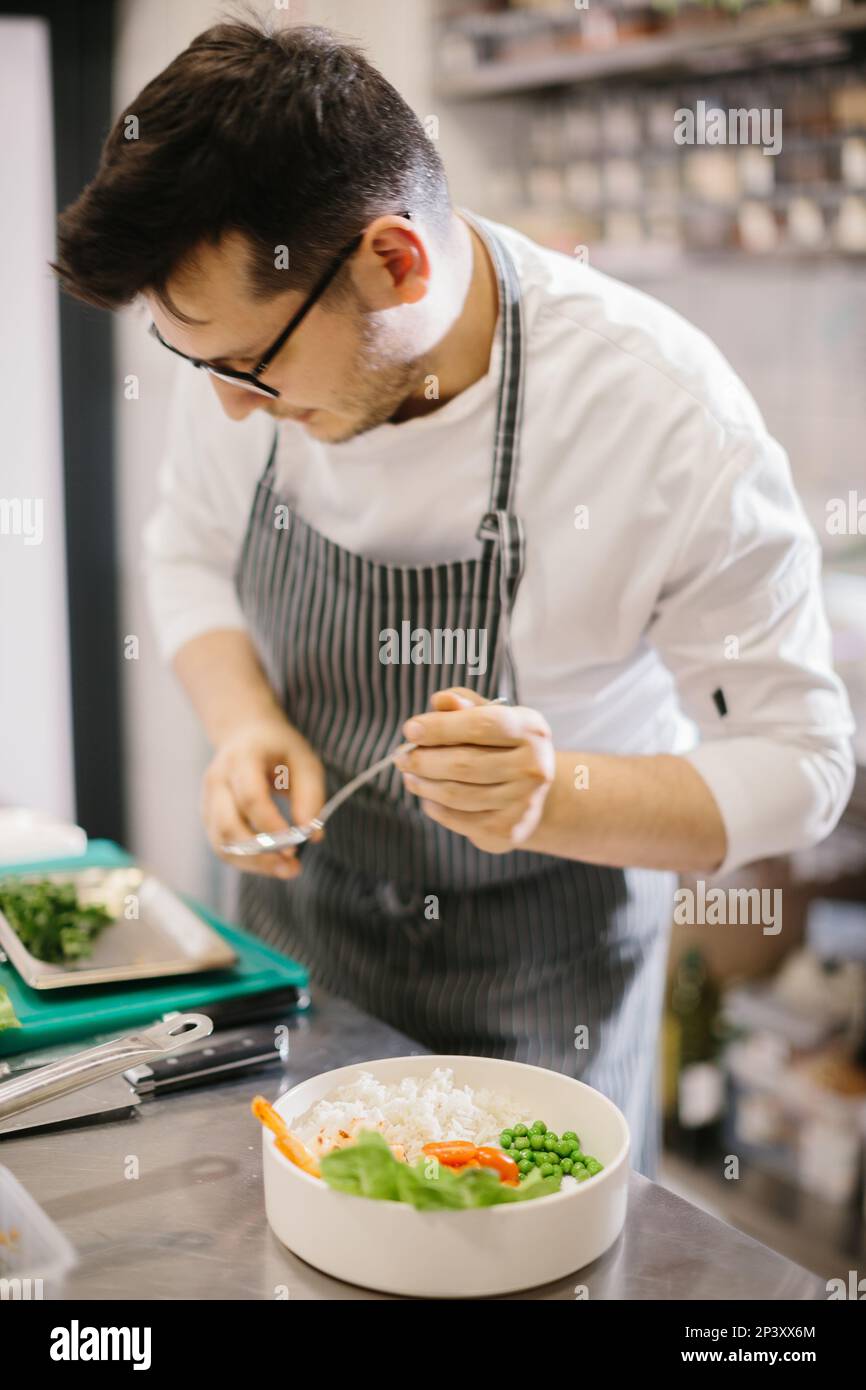 Preparing a bowl of seafood, a male chef prepares a delicious dish in a ...