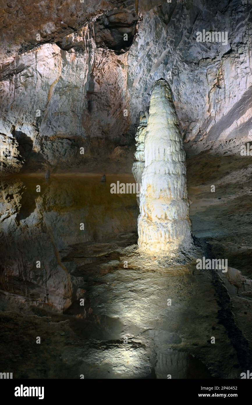 Large limestone stalagmite reflected in tranquil cave pool inside ...