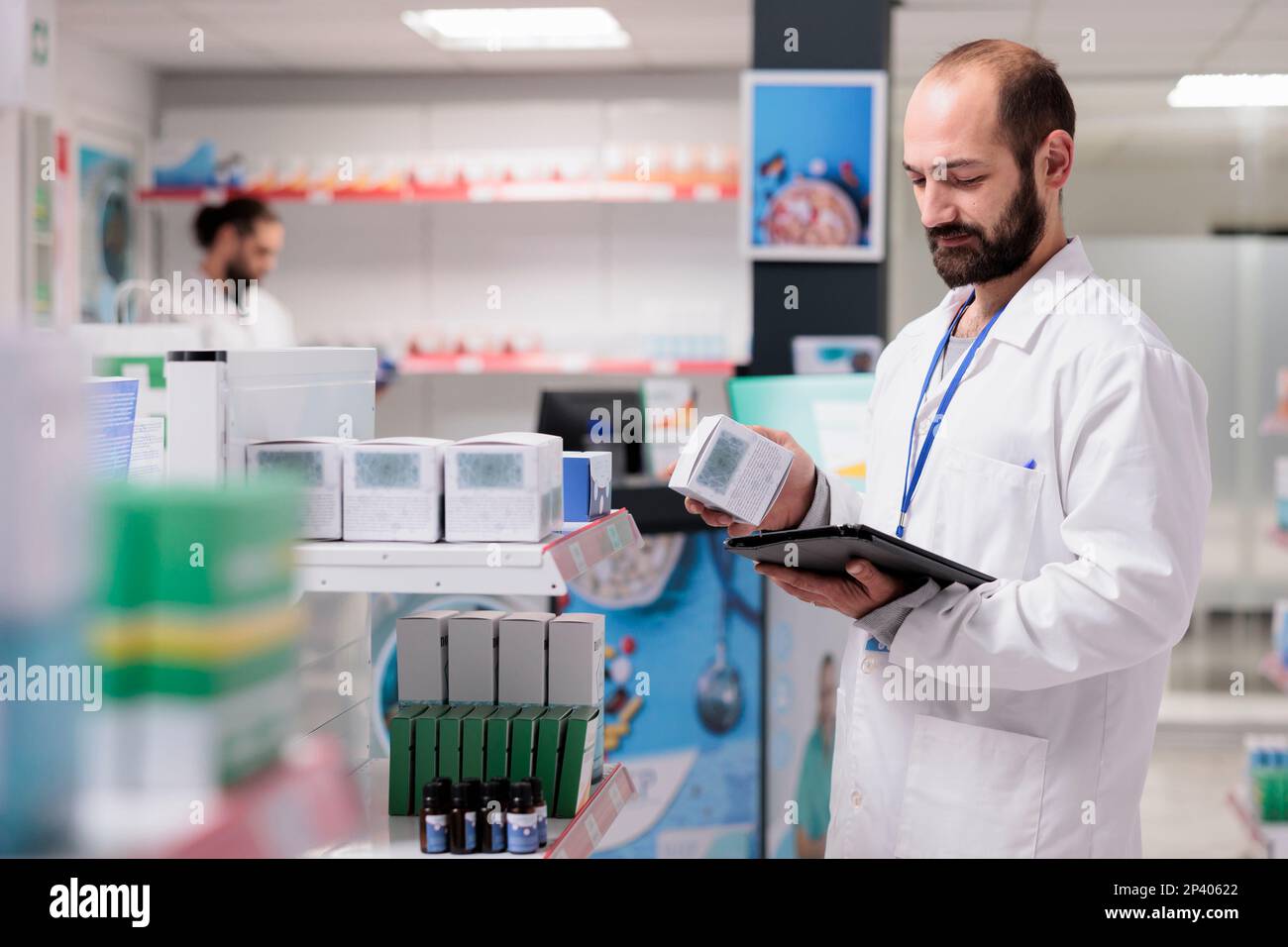 Drugstore employee looking at drugs packages typing medicaments name on ...