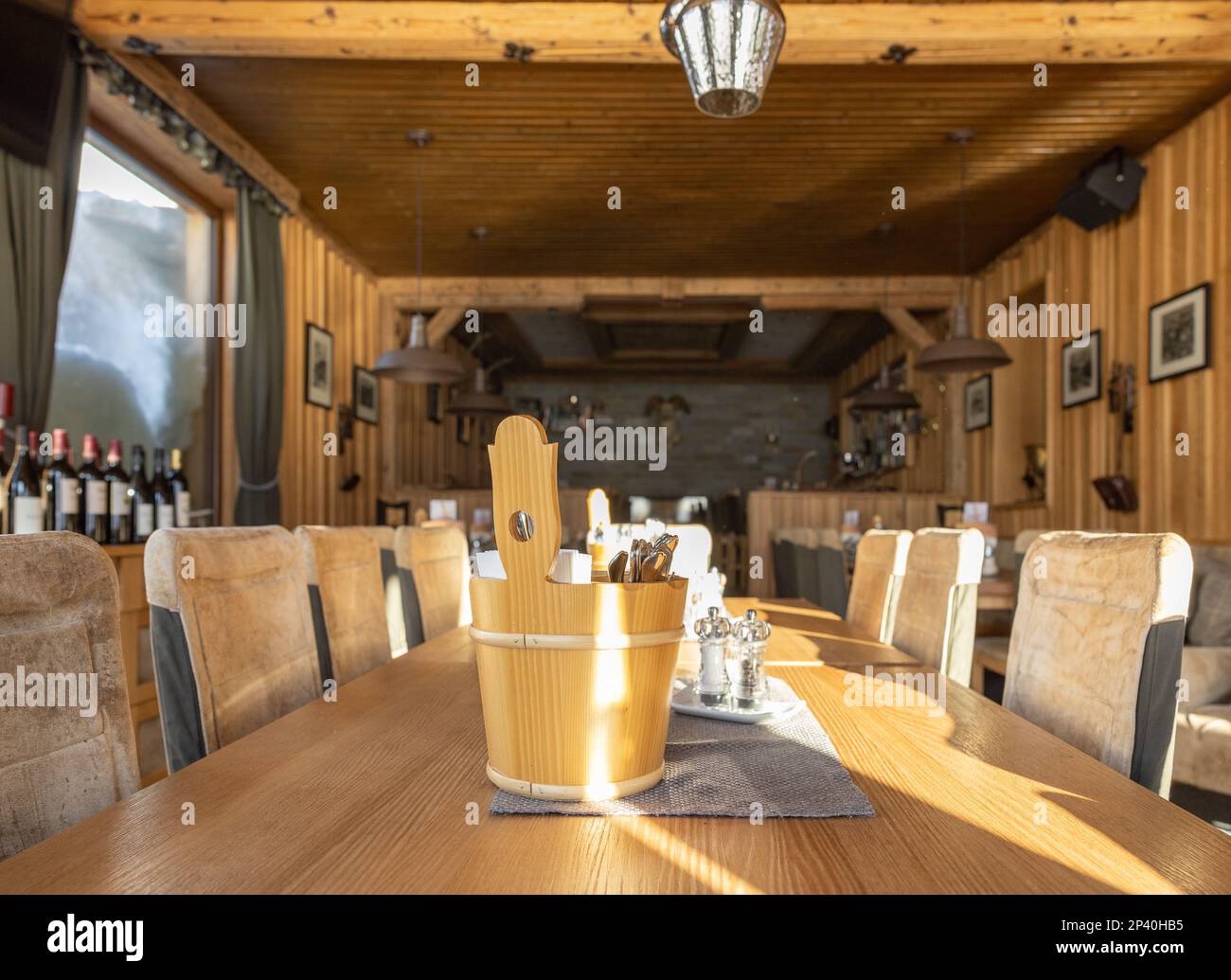 Hall of a sunlit Alpine restaurant with wooden and leather trim ...