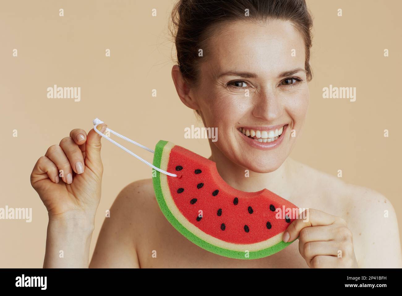 happy modern woman with watermelon shower sponge isolated on beige ...