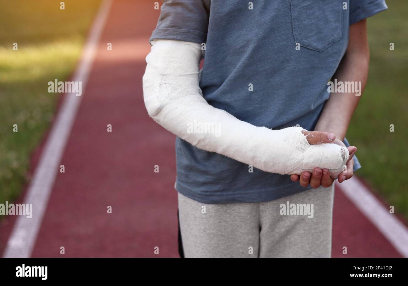cropped photo of little boy with broken hand outdoors on sports ground ...