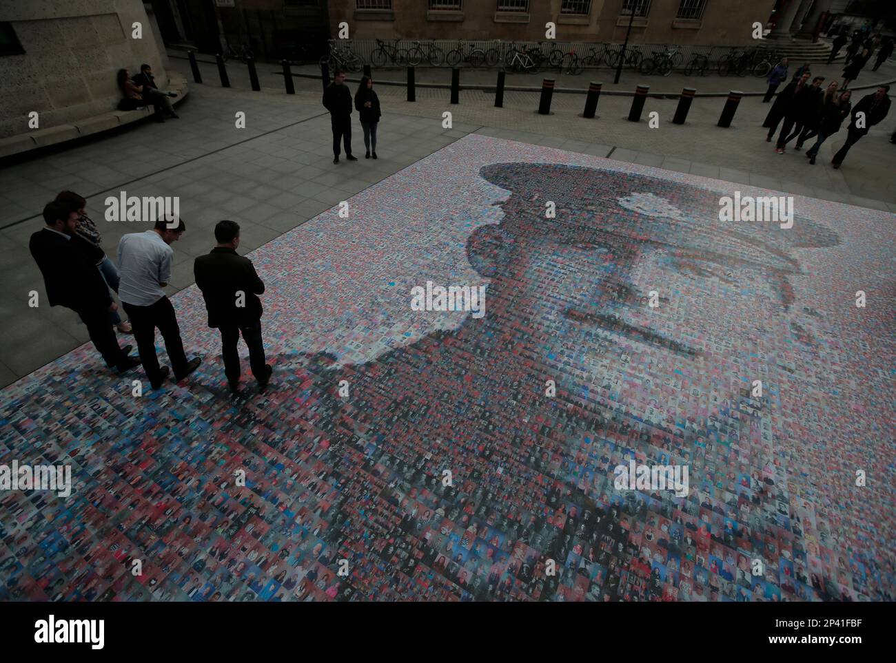People walk on and around a digital mosaic of photographs of people ...