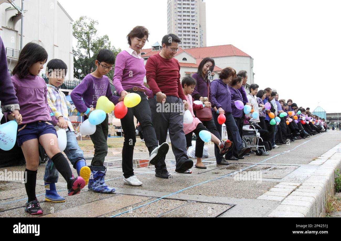Participants perform a line dance on the bank of the Muko River, in ...