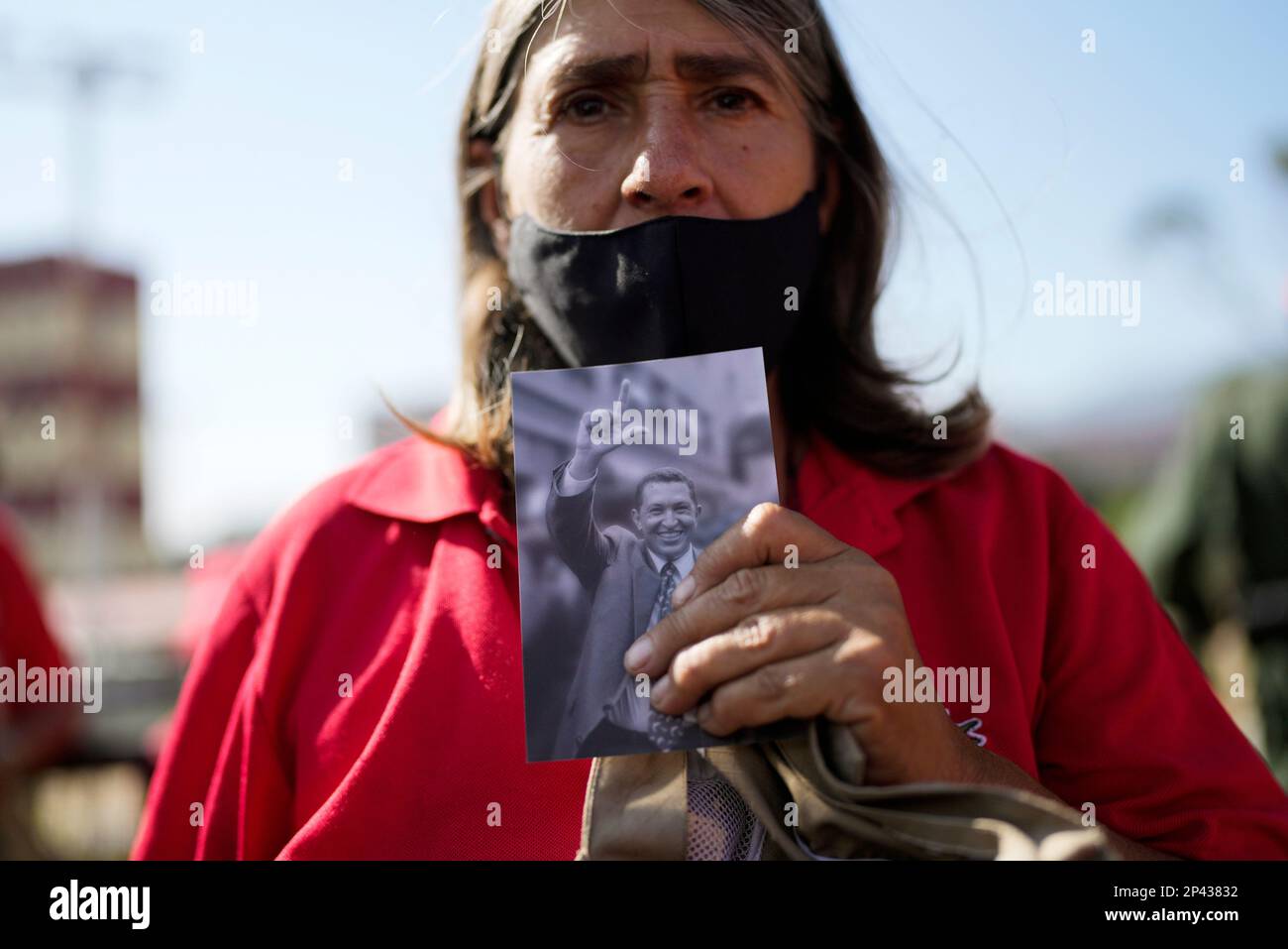 A woman holds a picture of late Venezuelan President Hugo Chavez as she ...