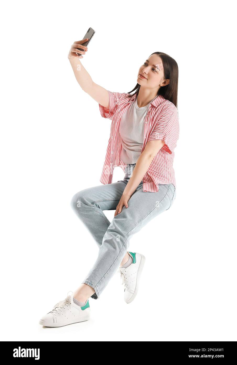 Pretty young woman with smartphone taking selfie while sitting on chair ...