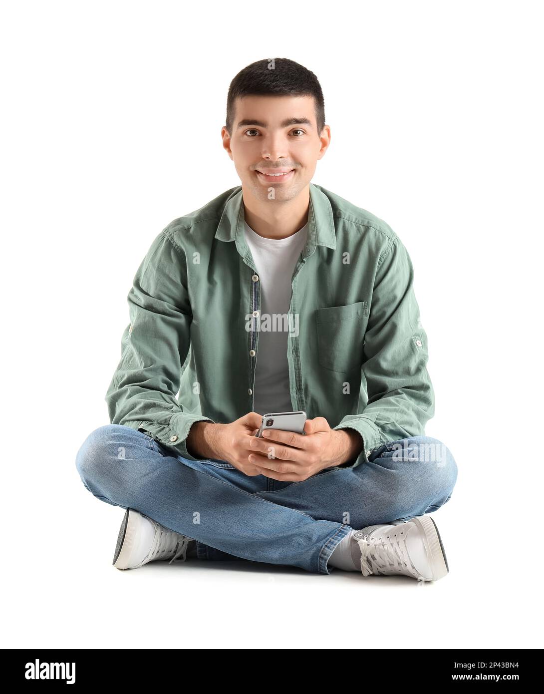 Young guy with mobile phone sitting on white background Stock Photo - Alamy