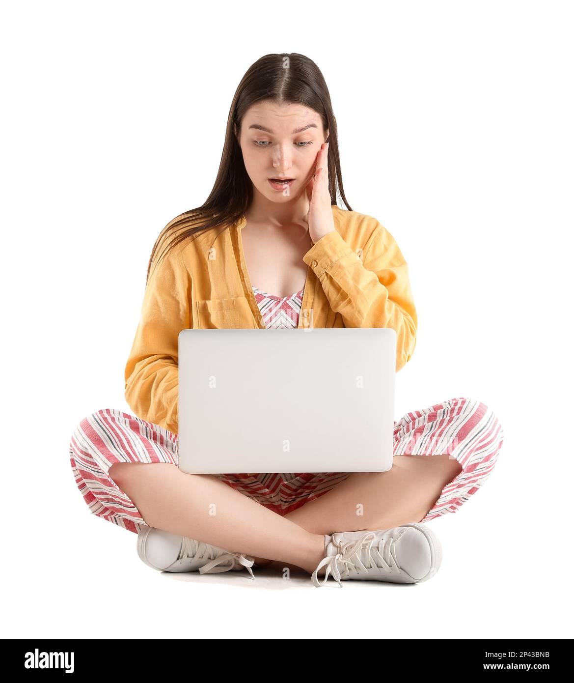 Surprised young woman with laptop sitting against white background ...