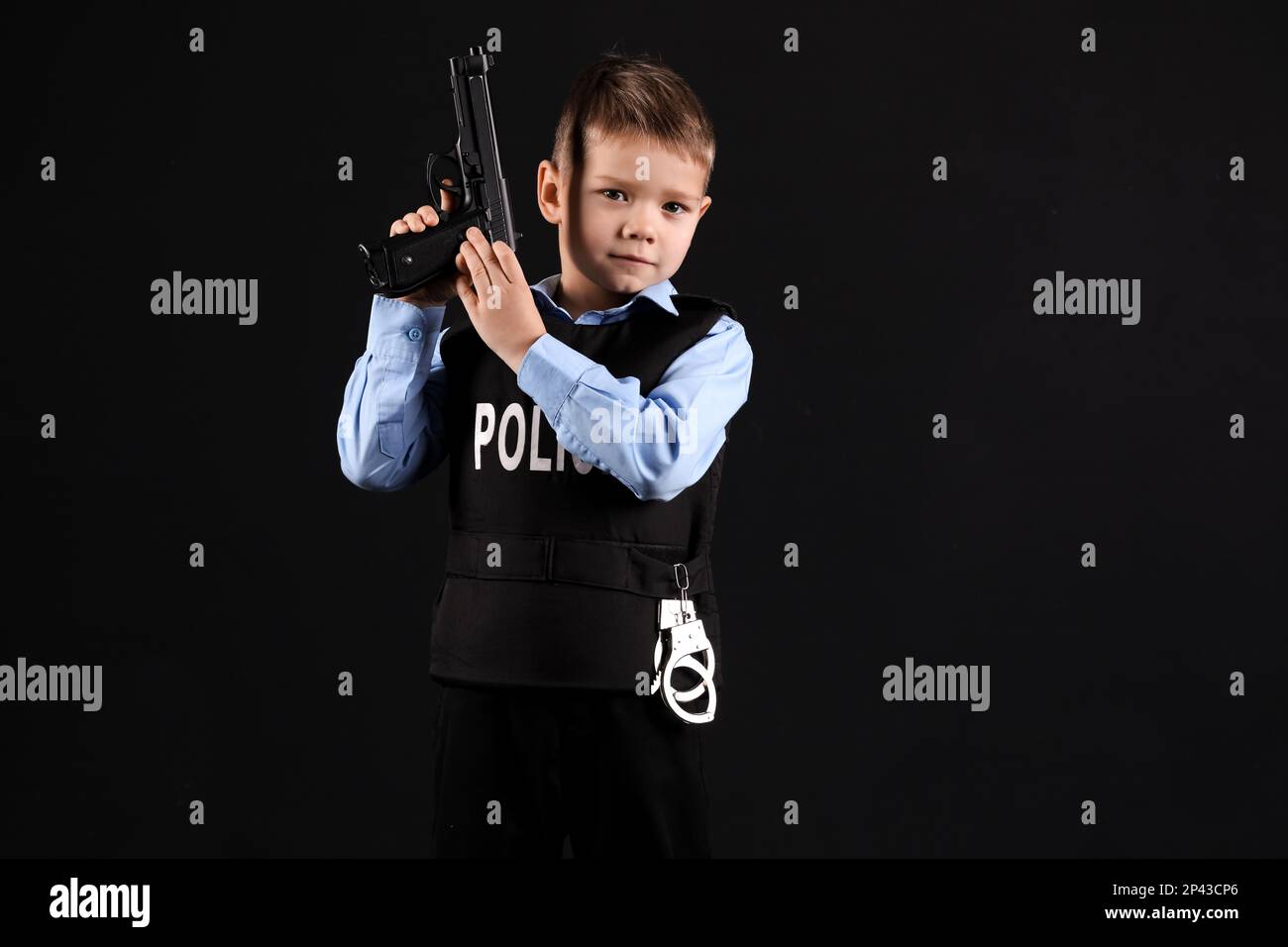Cute little police officer with gun on black background Stock Photo - Alamy