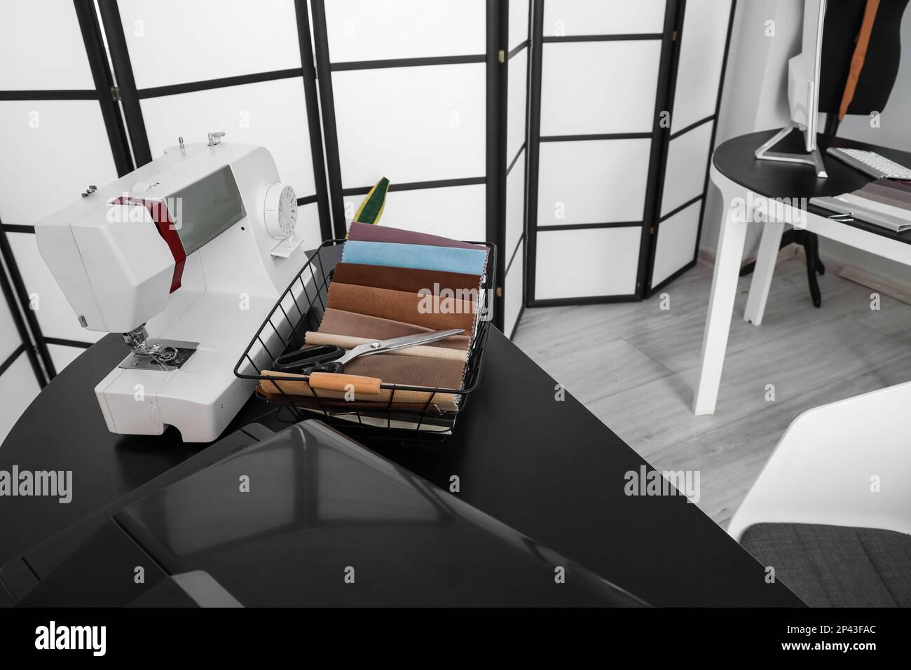 Tailor's workplace with sewing machine and fabric samples in atelier ...