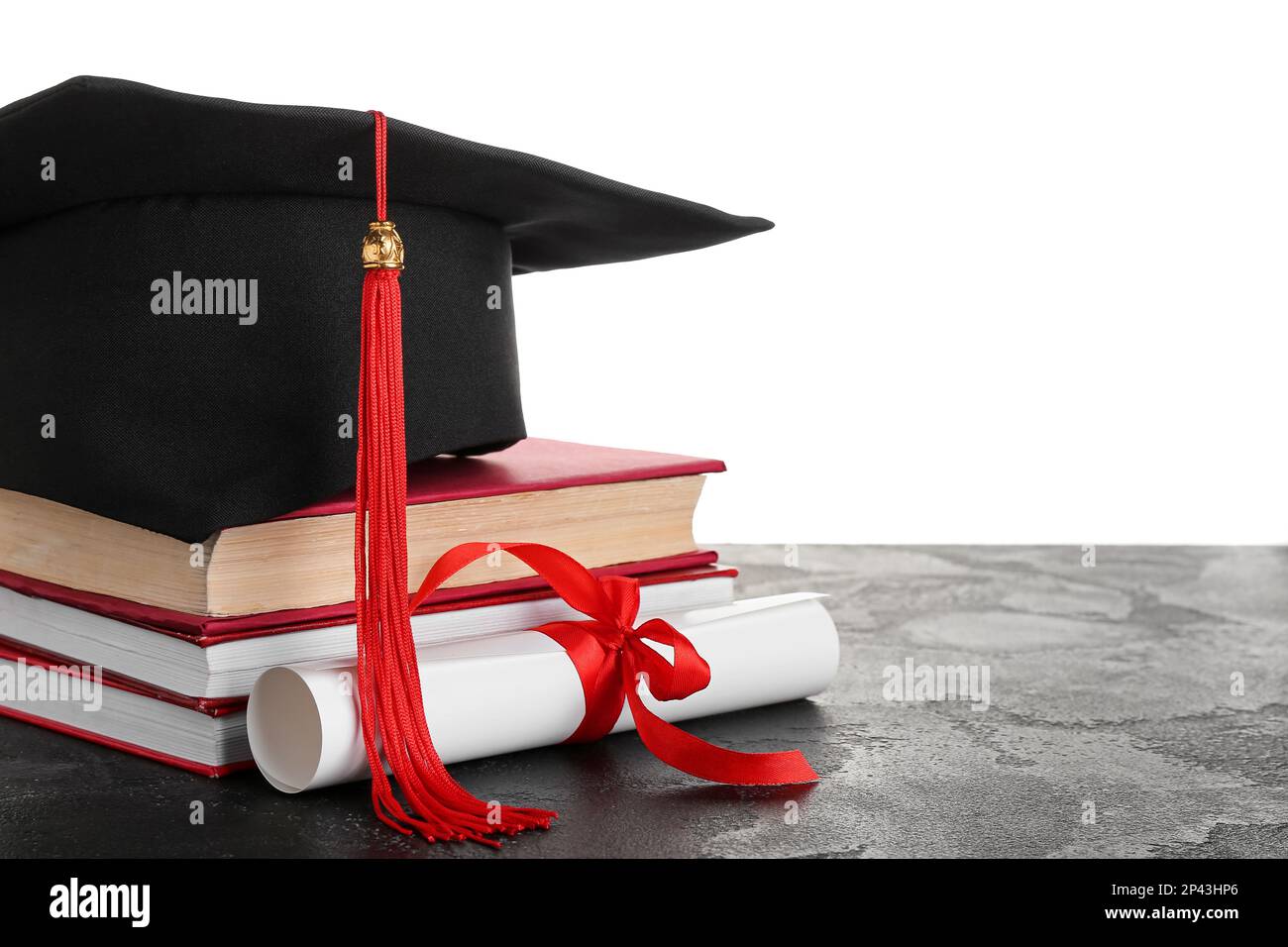 Graduation hat with diploma and books on dark table against white ...