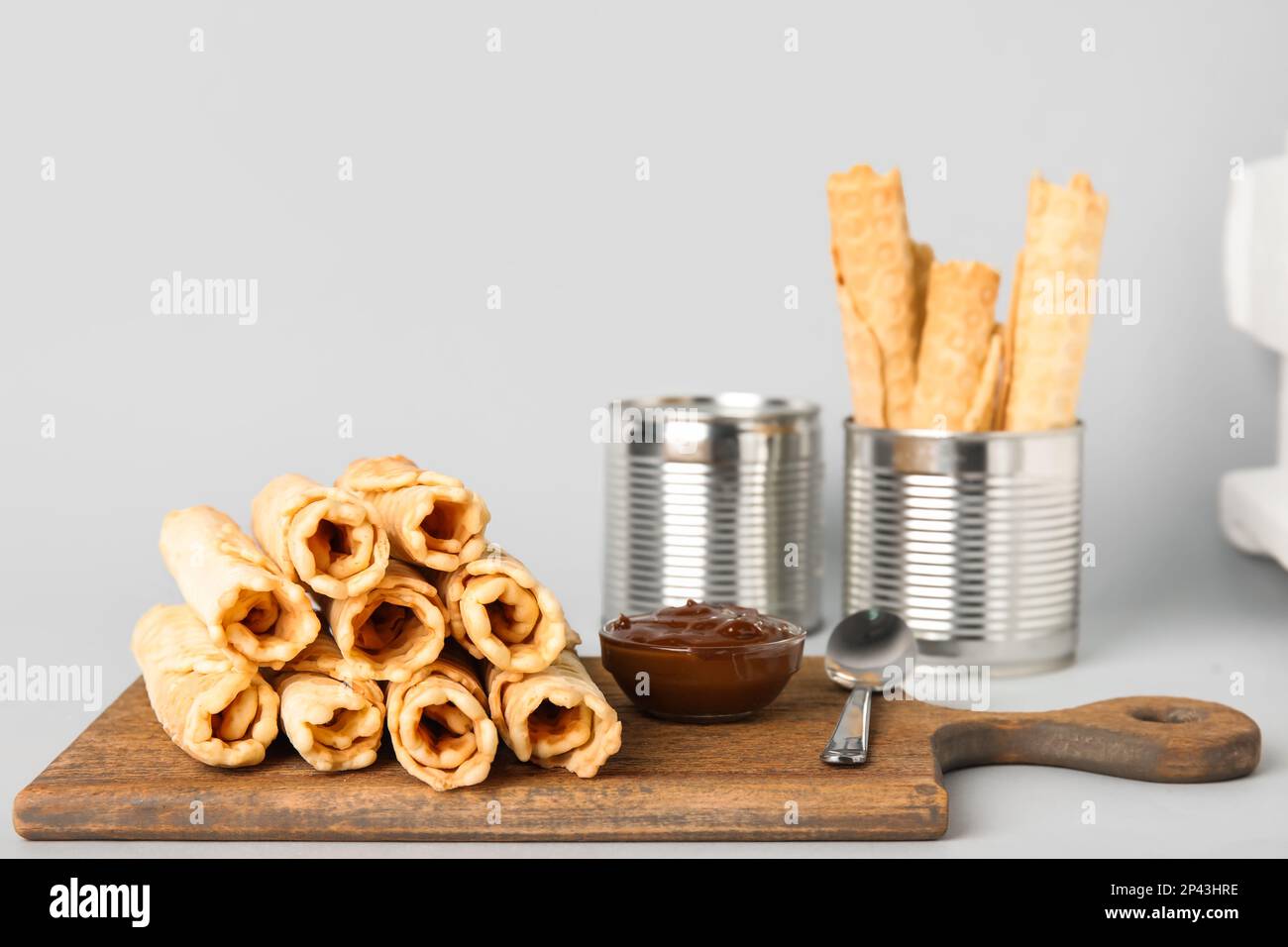 Board with stack of delicious wafer rolls on grey background Stock ...