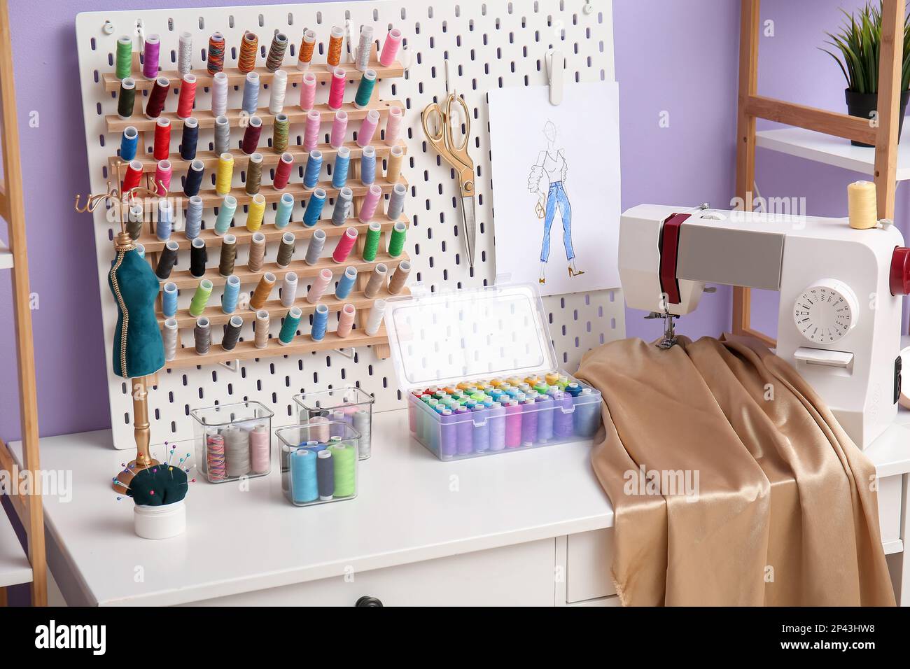 Tailor's workplace with sewing machine, pegboard and thread spools in ...