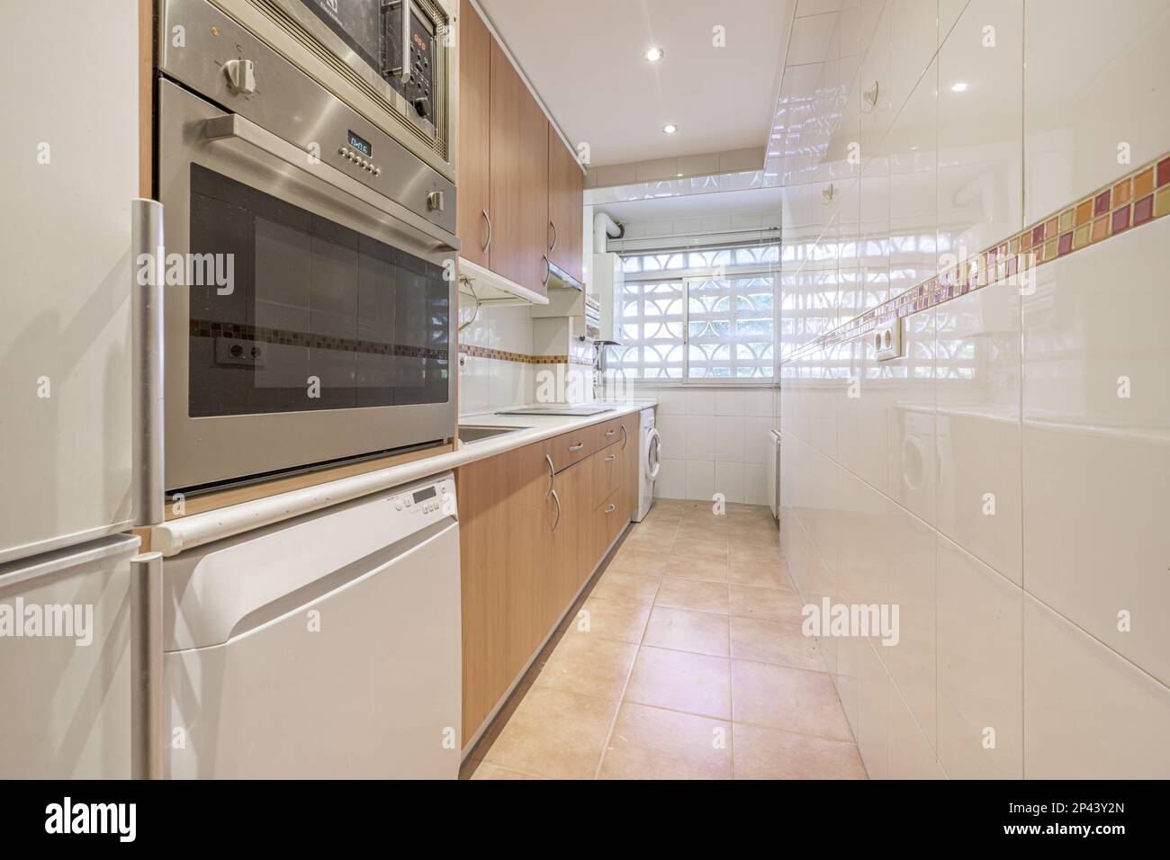 Elongated kitchen with wooden furniture, white countertops, cement ...