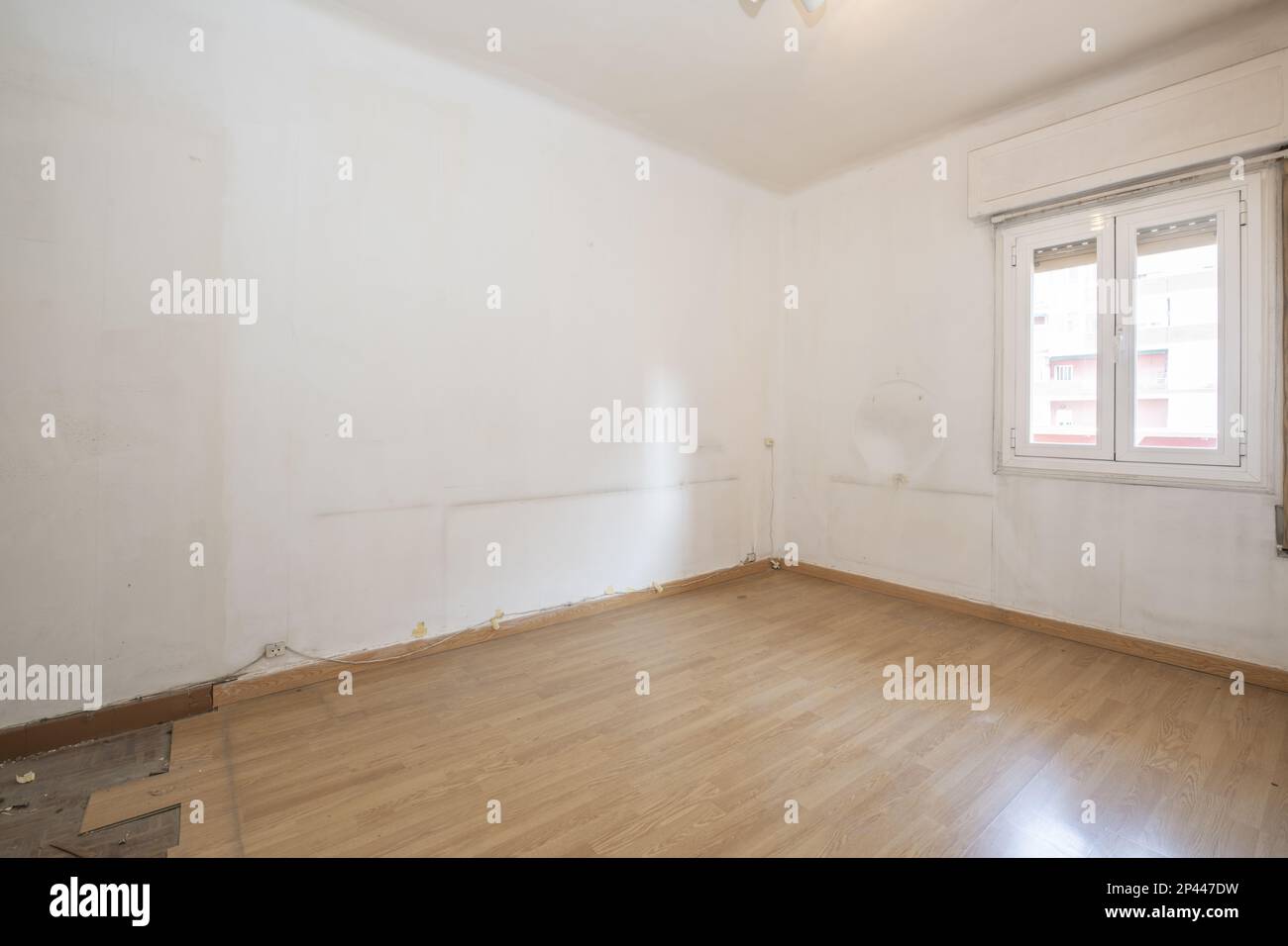 Empty room with poorly installed oak flooring white aluminum window and ...