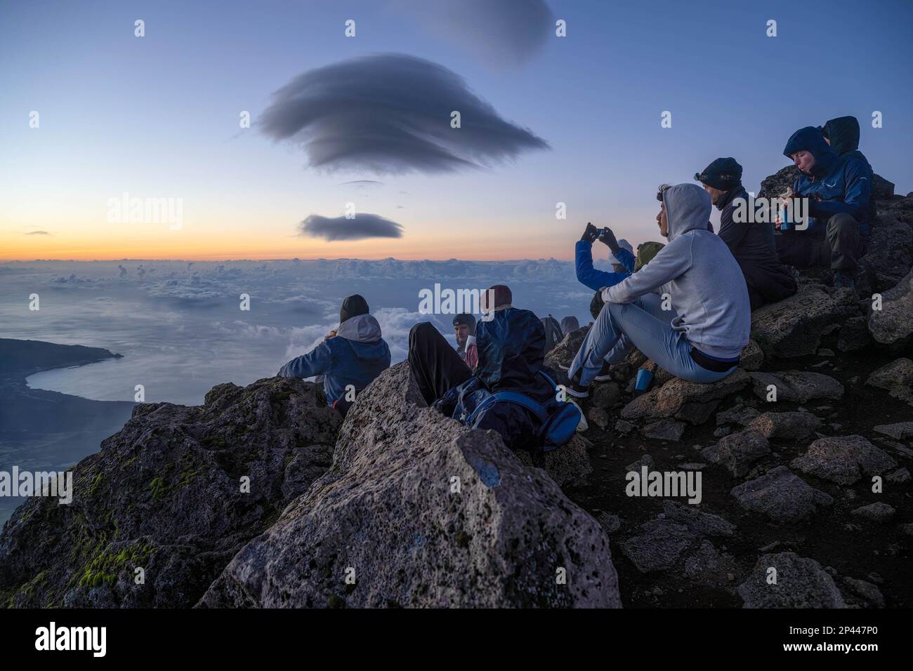 Hikers seen on the Pico mountain summit during sunrise, in the Azores ...