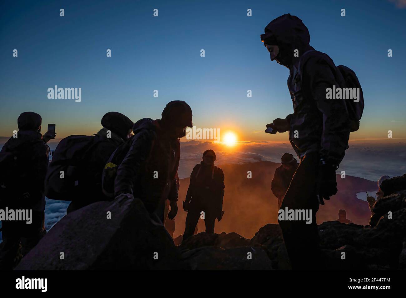 Hikers seen on the Pico mountain summit during sunrise, in the Azores ...