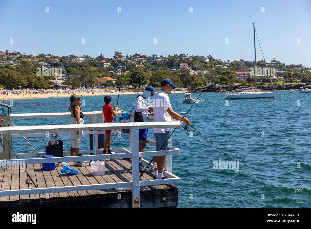 Family fishing in the ocean off a timber wharf at Balmoral Beach in ...