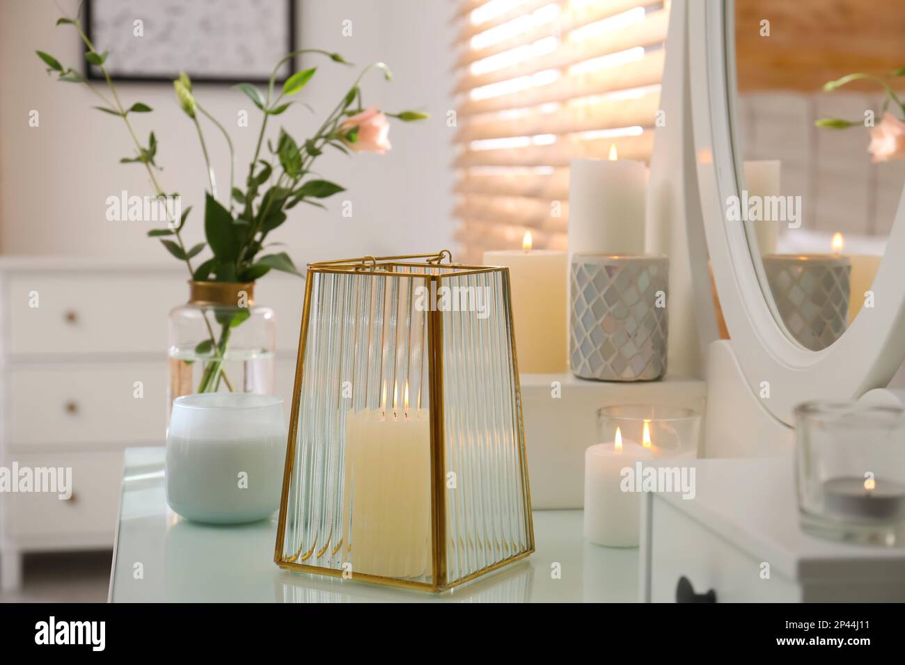 Burning scented candles and bouquet on dressing table indoors Stock ...
