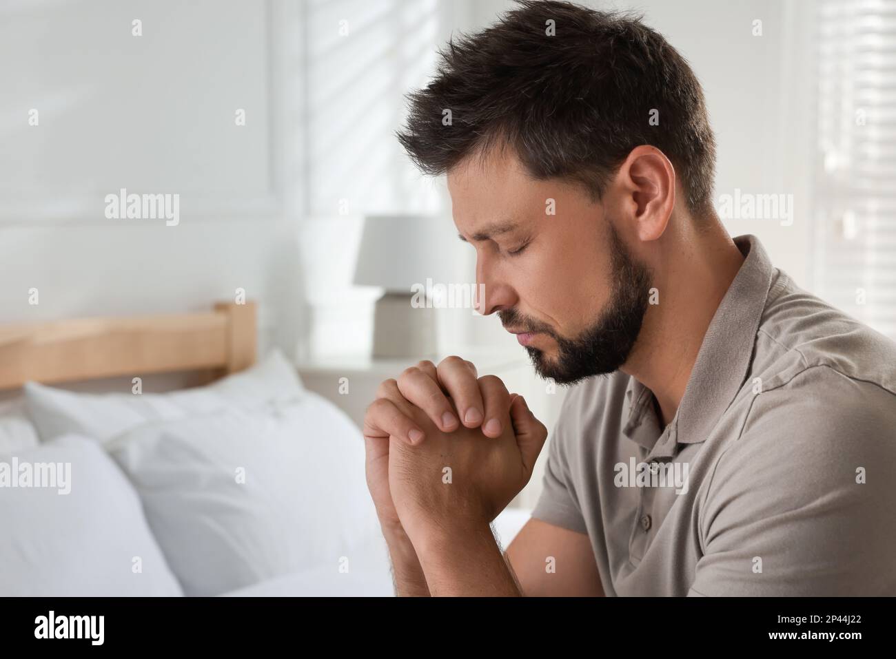 Religious man praying in bedroom. Space for text Stock Photo - Alamy
