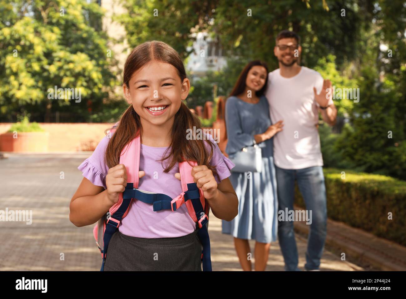 Parents waving goodbye to their daughter before school outdoors Stock ...