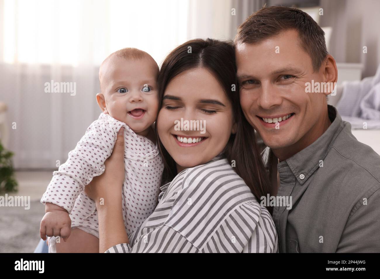Happy family with their cute baby in living room at home Stock Photo ...