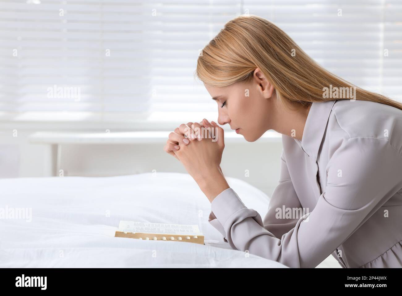 Religious young woman with Bible praying in bedroom. Space for text Stock Photo - Alamy