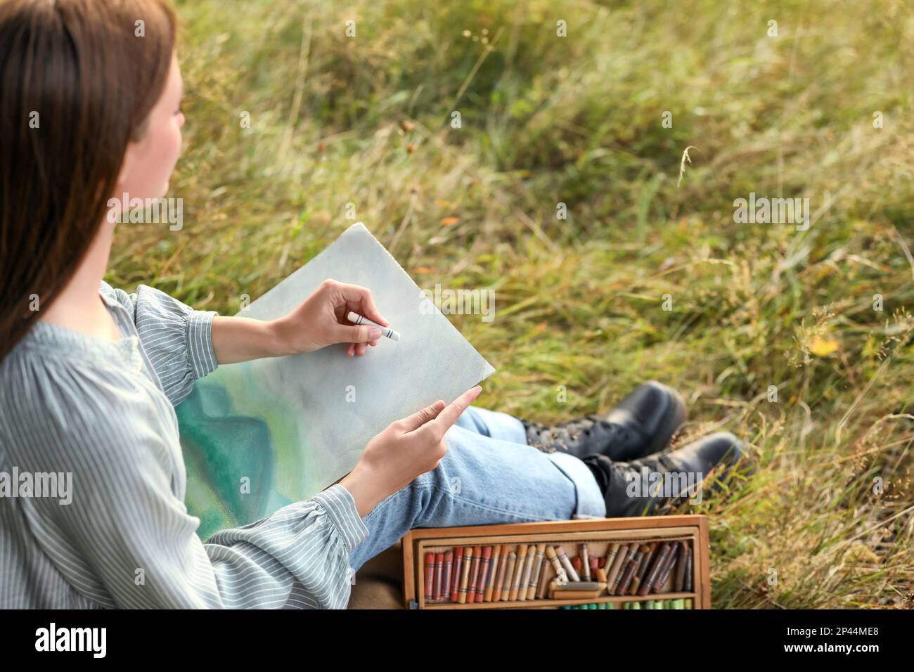 Young woman drawing landscape with soft pastels in nature. Space for ...