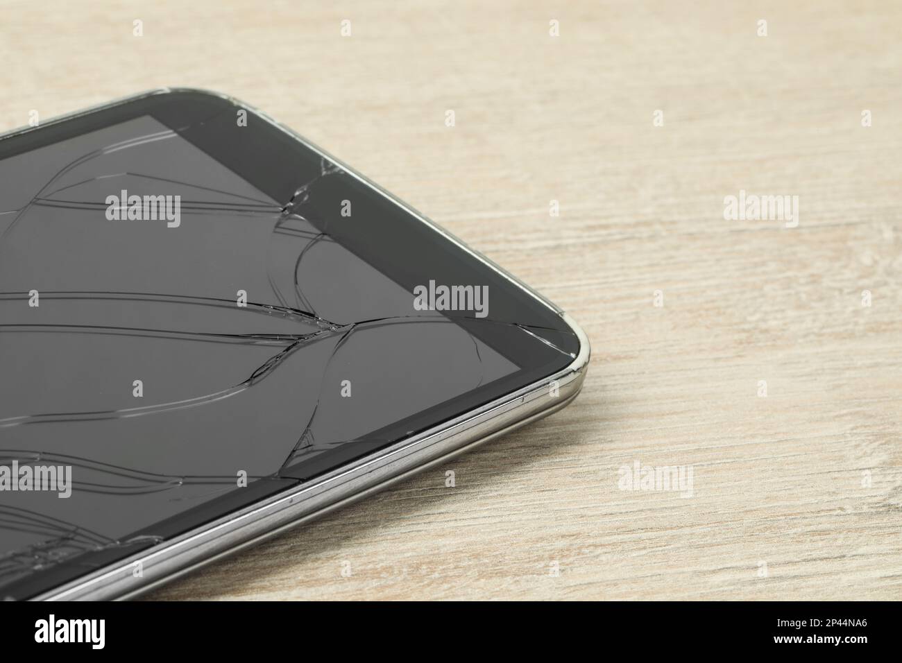 Smartphone with cracked screen on light beige wooden background ...