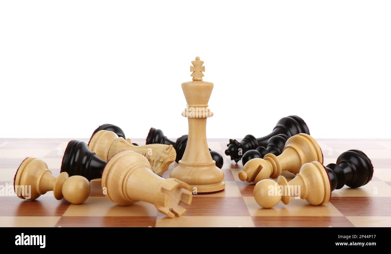 King among fallen chess pieces on wooden board against white background ...