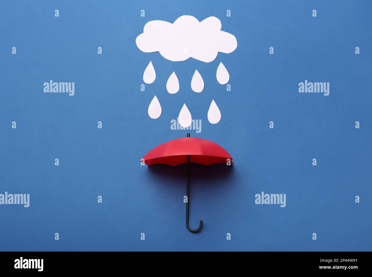Mini umbrella and paper raindrop cloud on blue background, flat lay ...