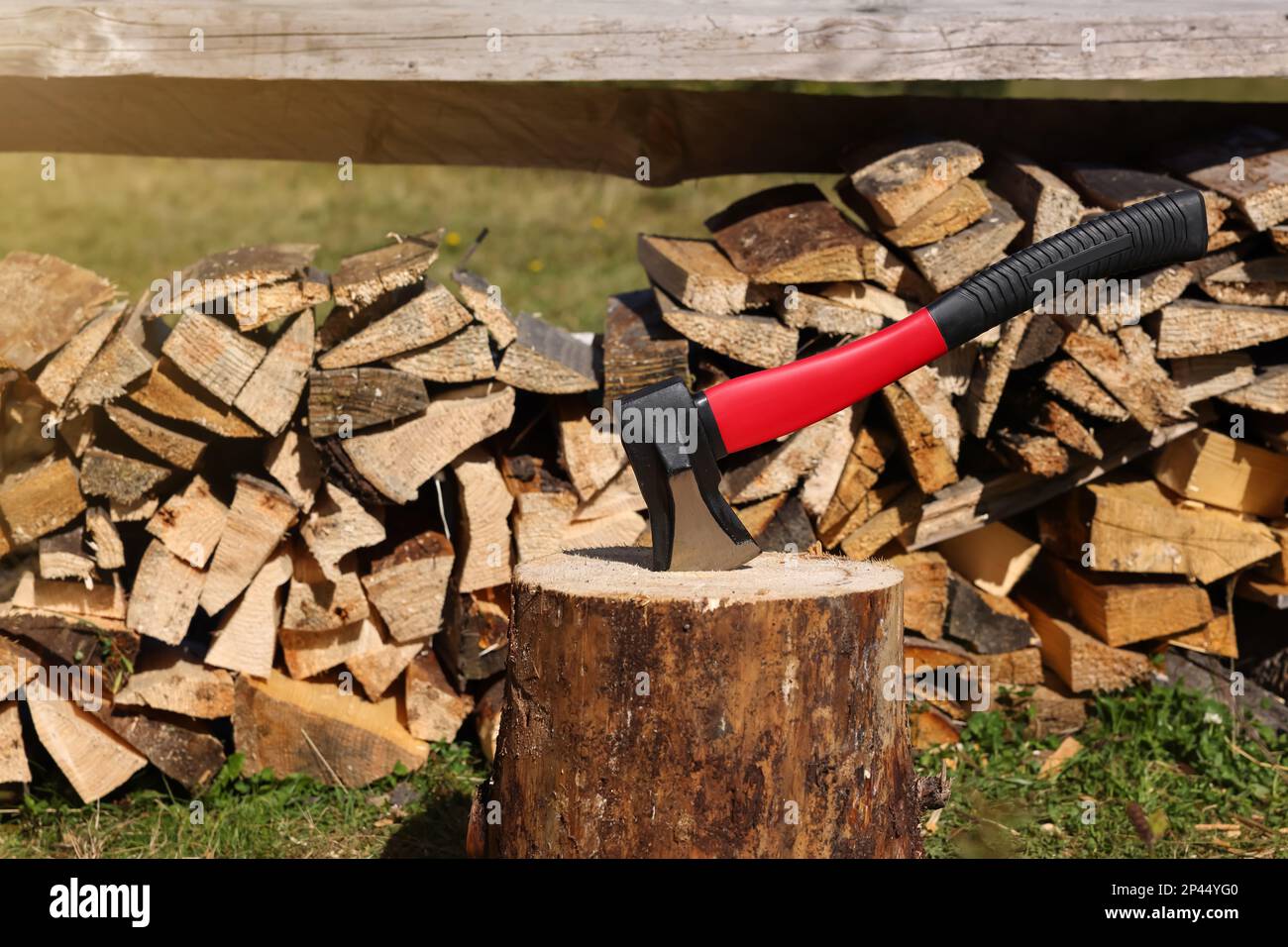 Tree stump with axe and cut firewood outdoors Stock Photo - Alamy