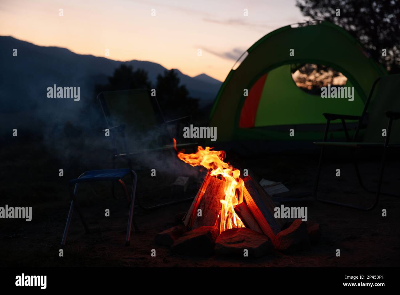 Beautiful bonfire and folding chairs near camping tent outdoors in ...