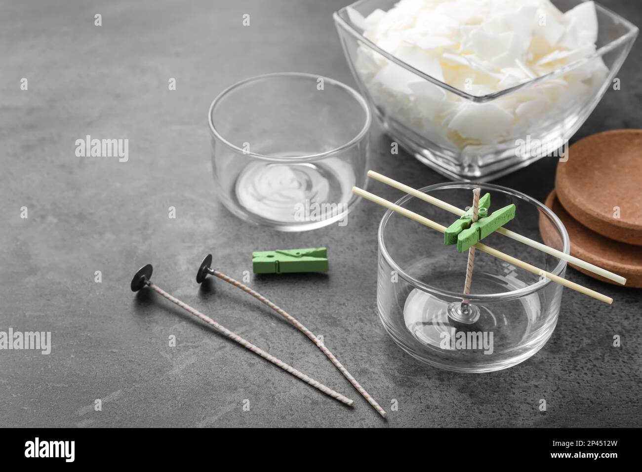 Glass containers with wicks and wax flakes on grey table. Making ...