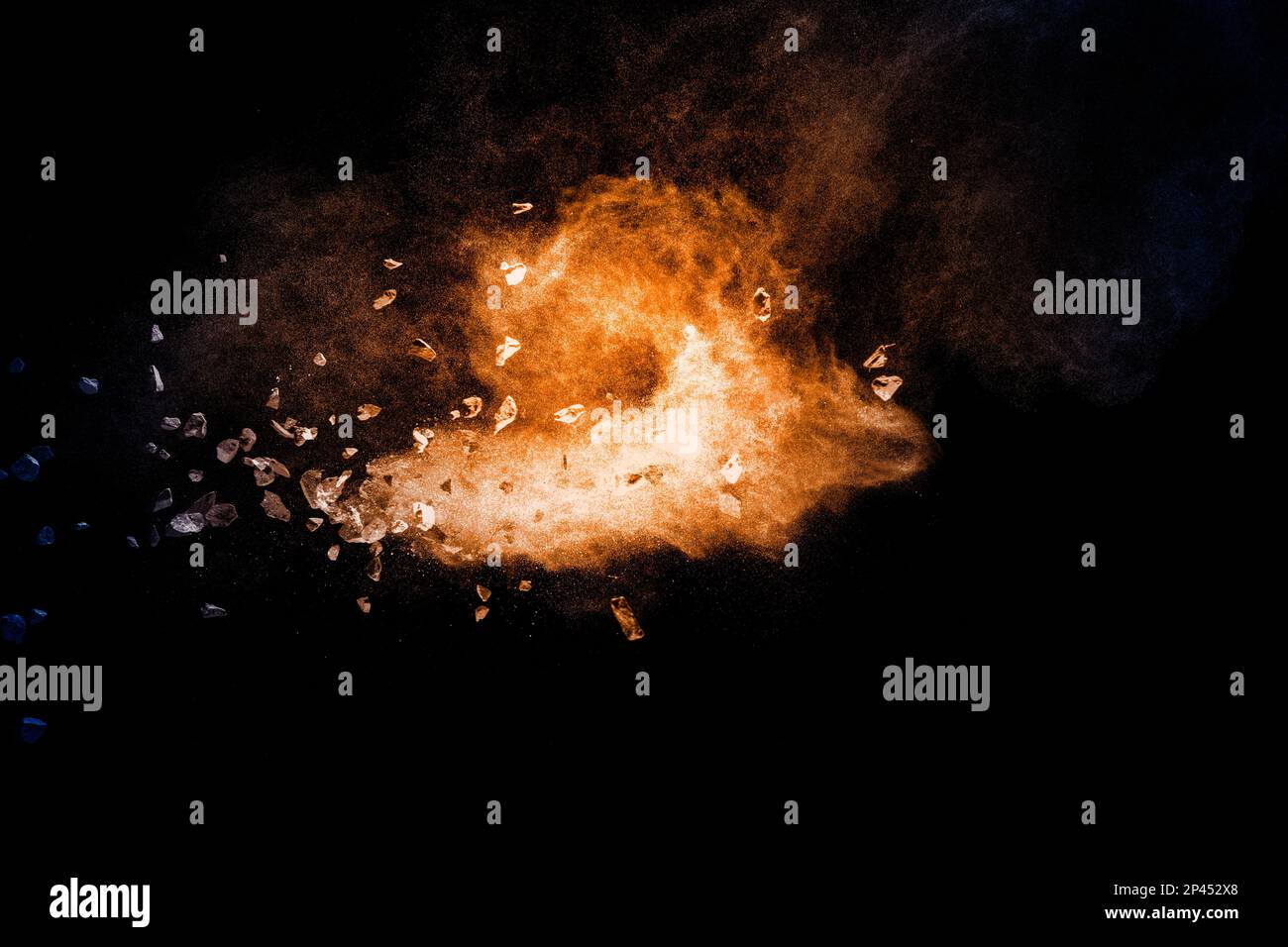 Split debris of stone exploding with orange dust against black ...
