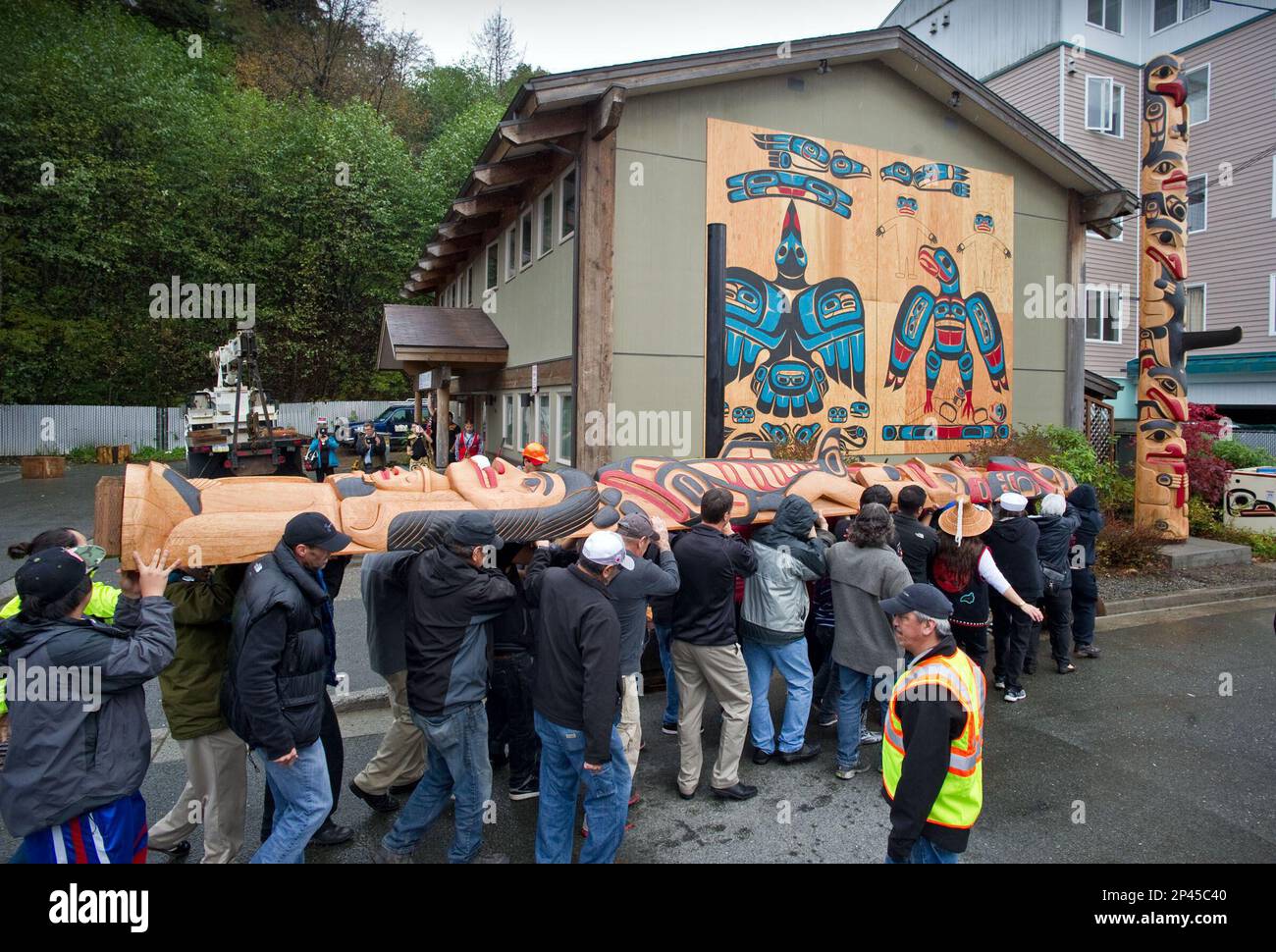 The Raven totem pole is carried to the front of the Gajaa Hít building ...