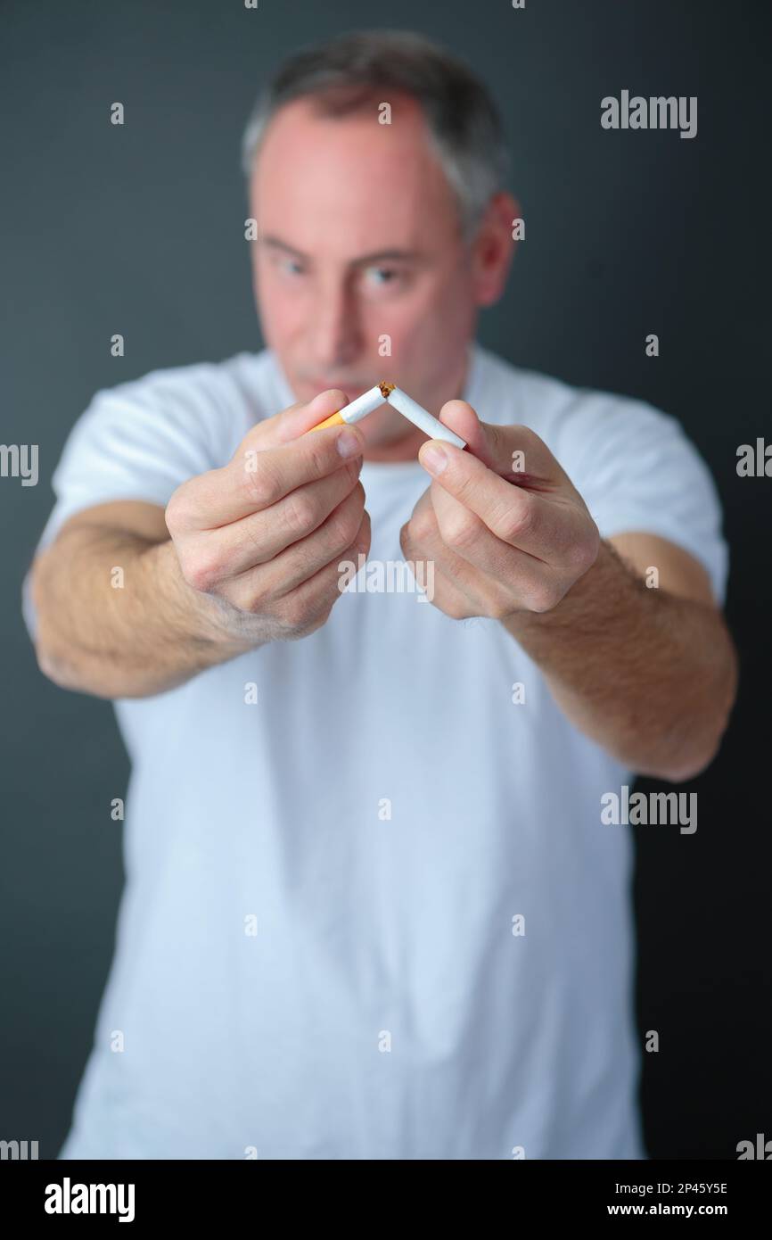 an adult man breaking cigarette Stock Photo - Alamy