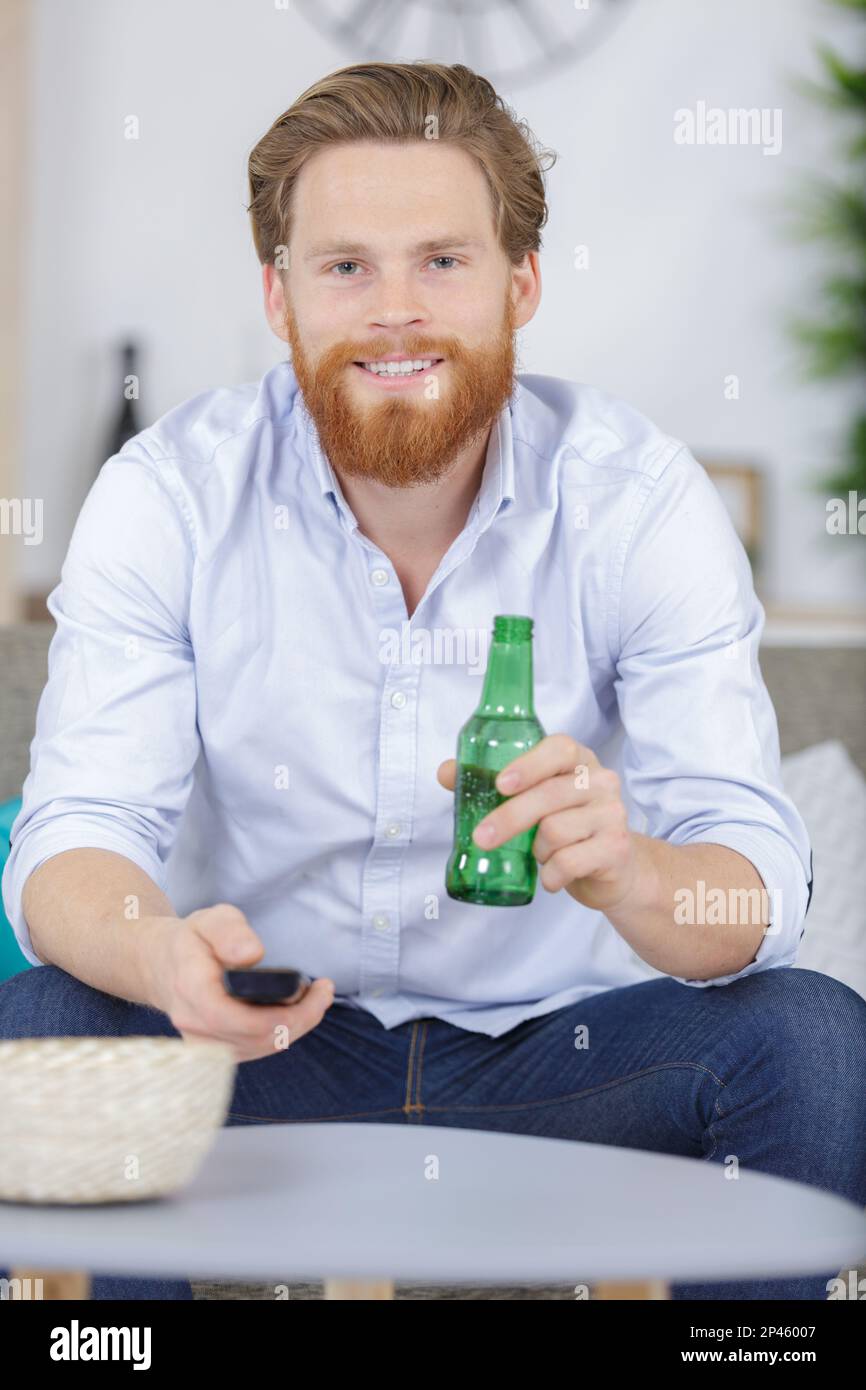 man holding a bottle of beer and the tv remote Stock Photo - Alamy