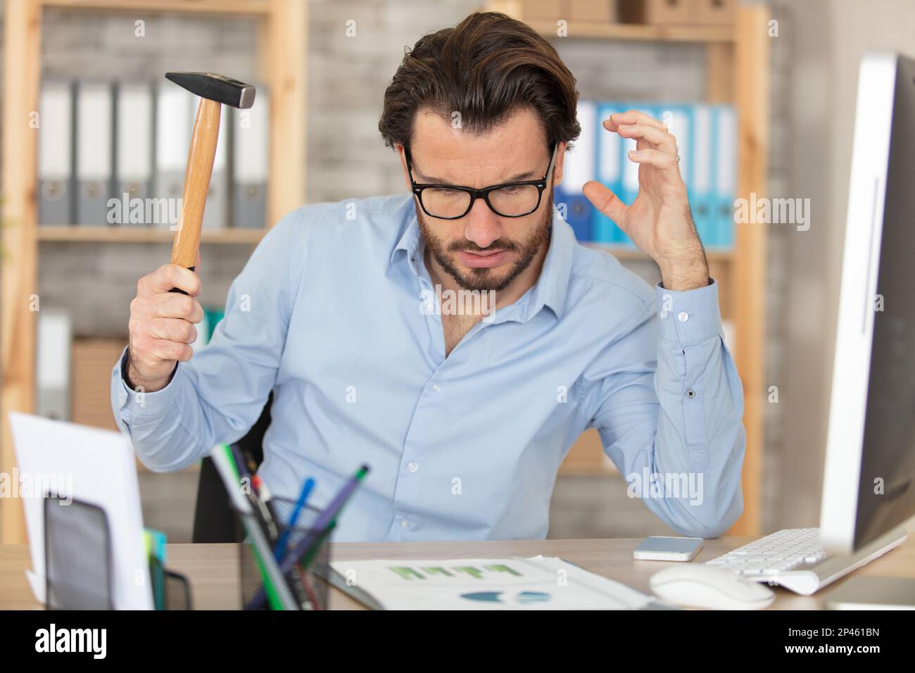 frustrated male office worker holds raised hammer Stock Photo - Alamy
