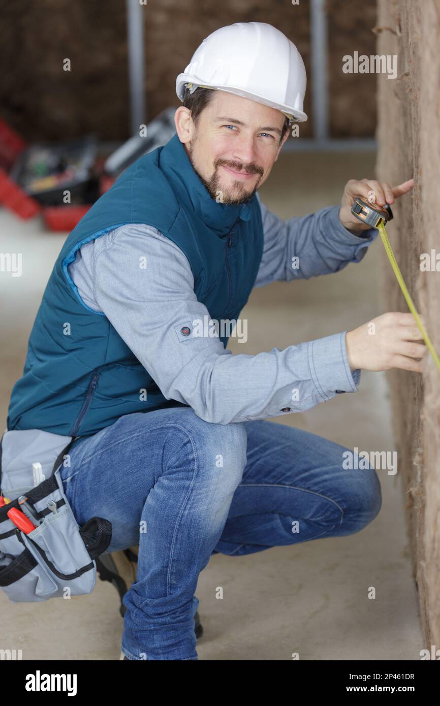 tradesman measuring wall packed with insulation Stock Photo - Alamy