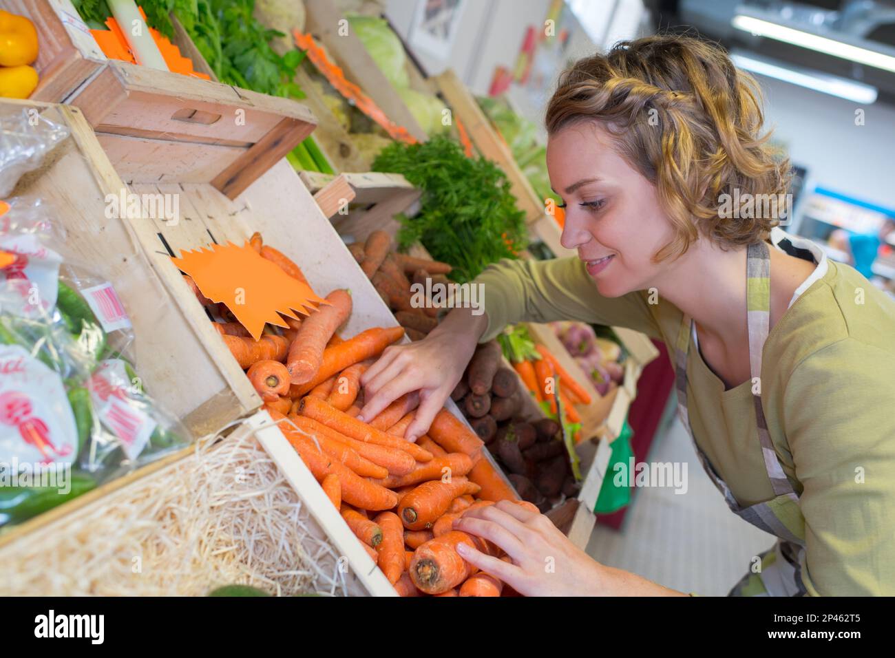 shop assistant sorting stock of carrots on display Stock Photo - Alamy