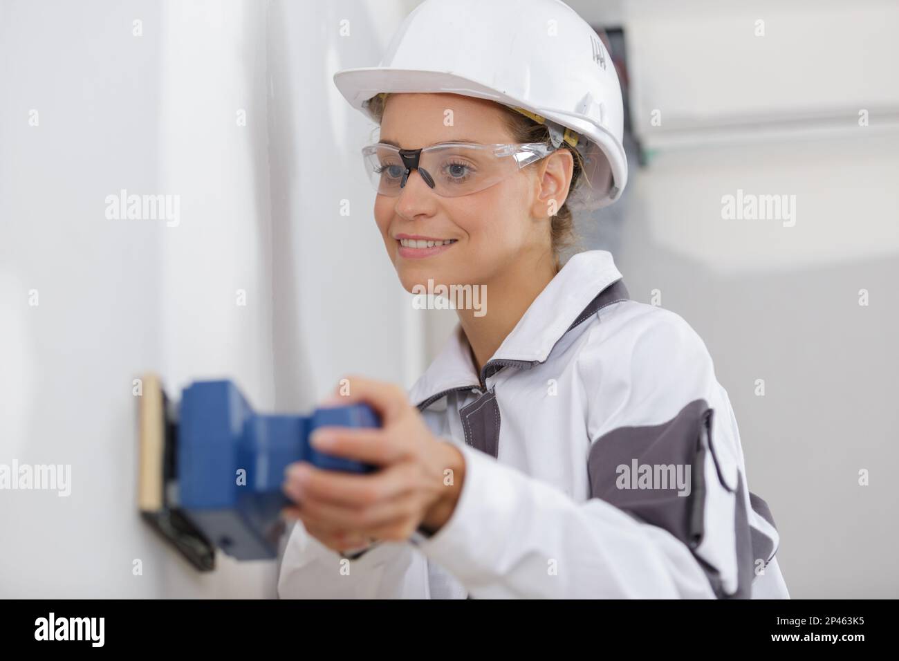 professional female builder using cordless sander on wall Stock Photo ...