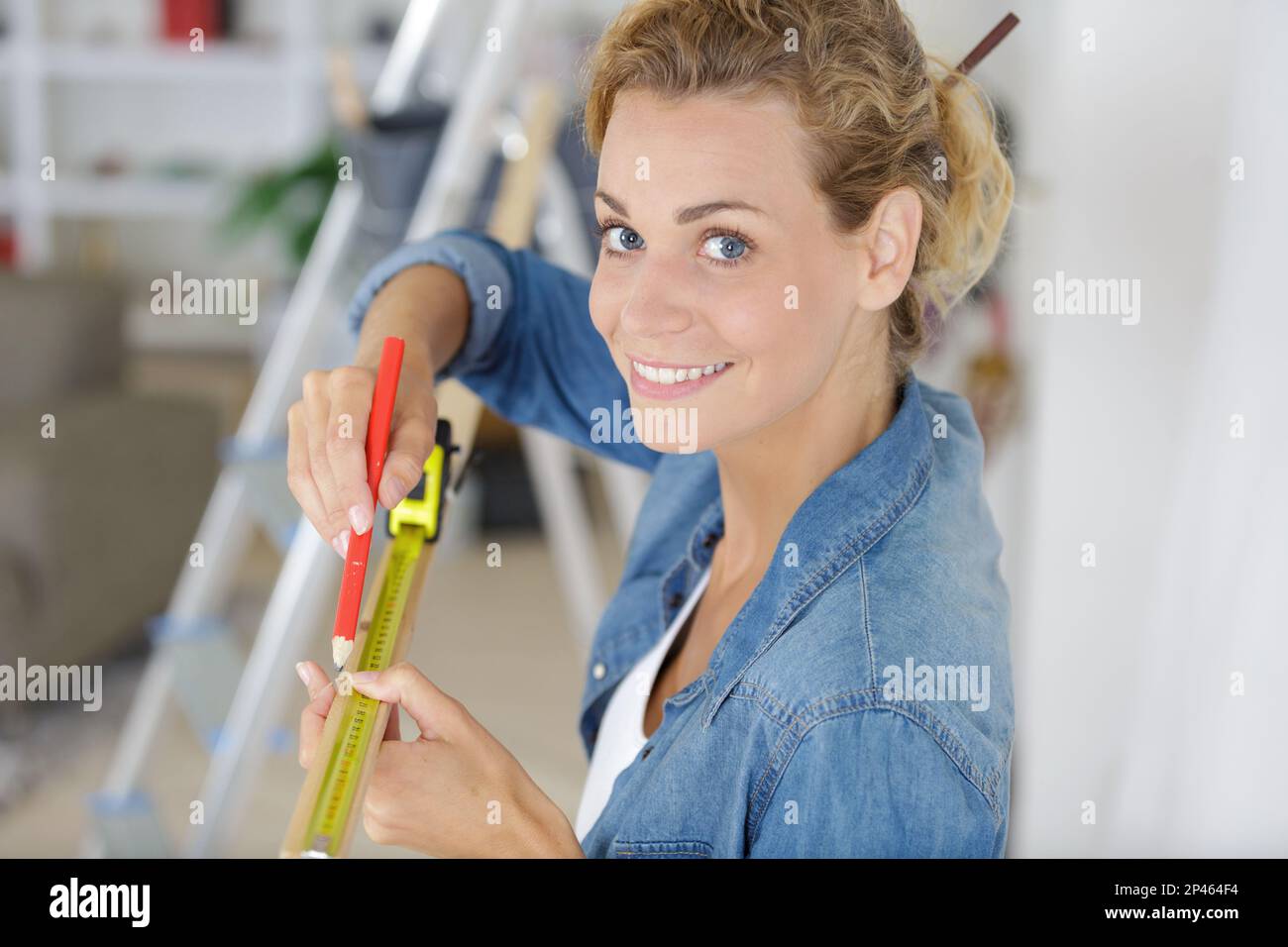 young woman measuring a wall with measuring tape Stock Photo - Alamy